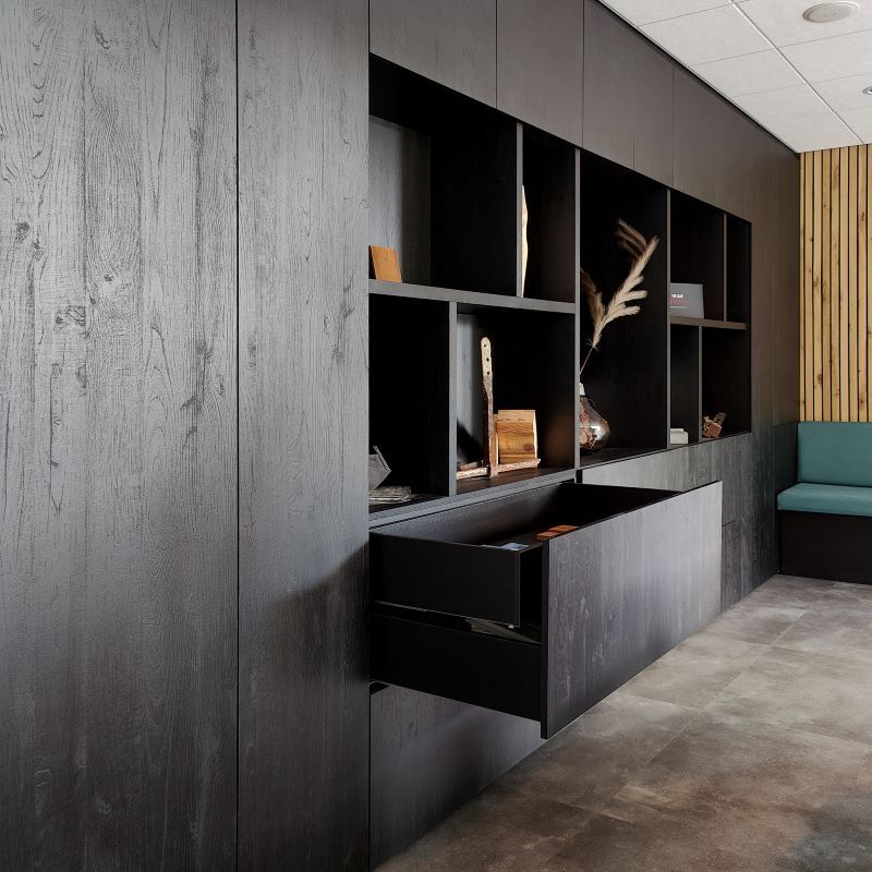 Zwarte wandkast in kantine met open en dichte delen